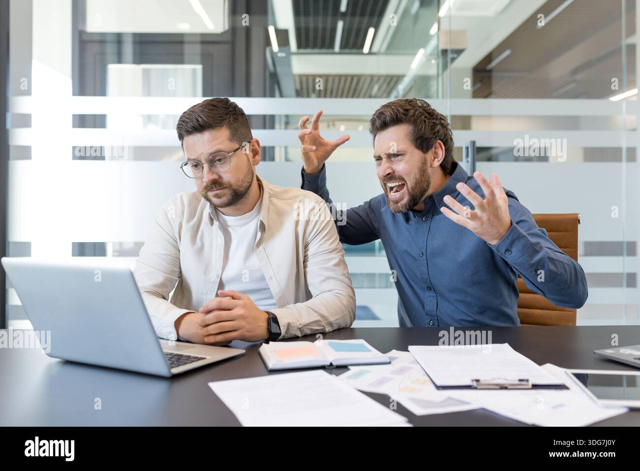 Frustrated boss or colleague yelling at a stressed employee in a modern ...