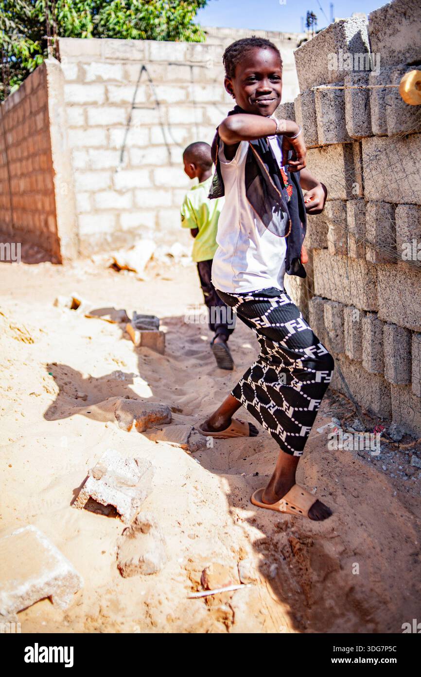 African child stands in the foreground in a casual urban setting during ...