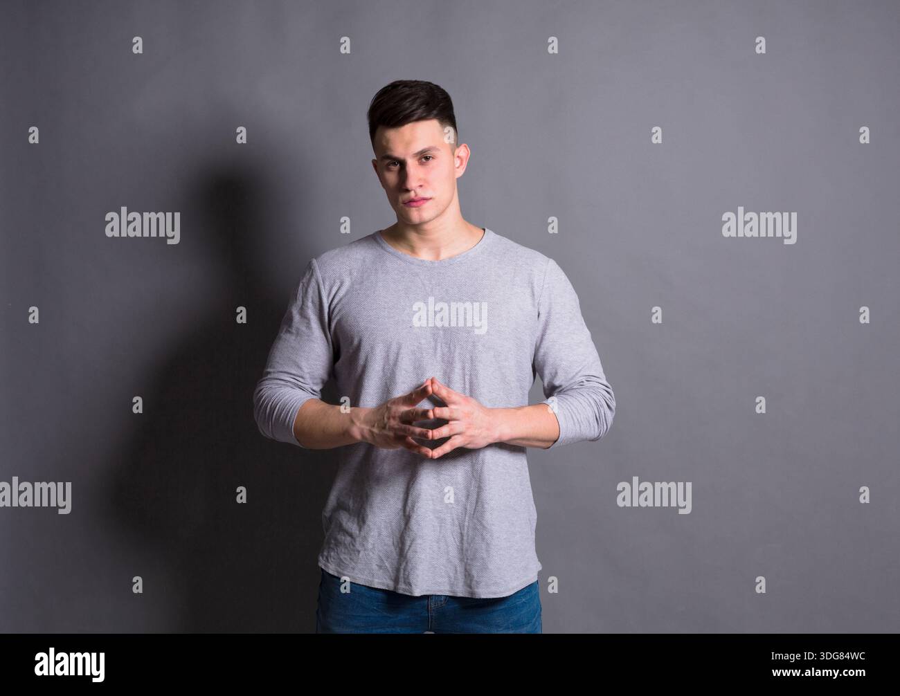 Confident Young Man Posing Against a Gray Background in Casual Attire ...