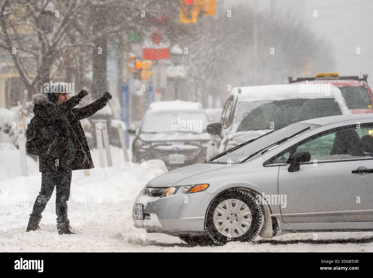 A man celebrates after helping push a stuck car out of a snowbank ...