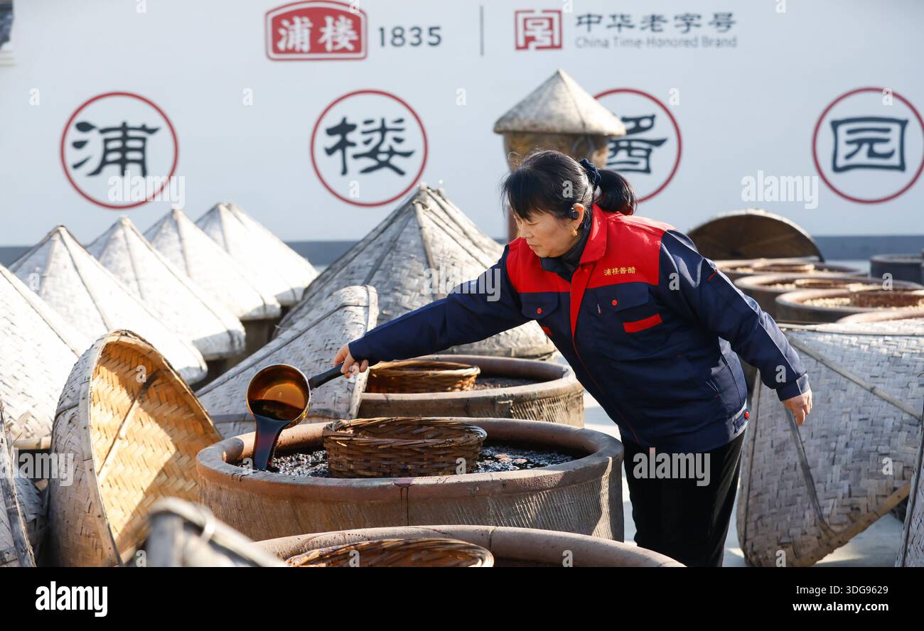 A worker checks the fermenting of sauce in the large vats at a ...