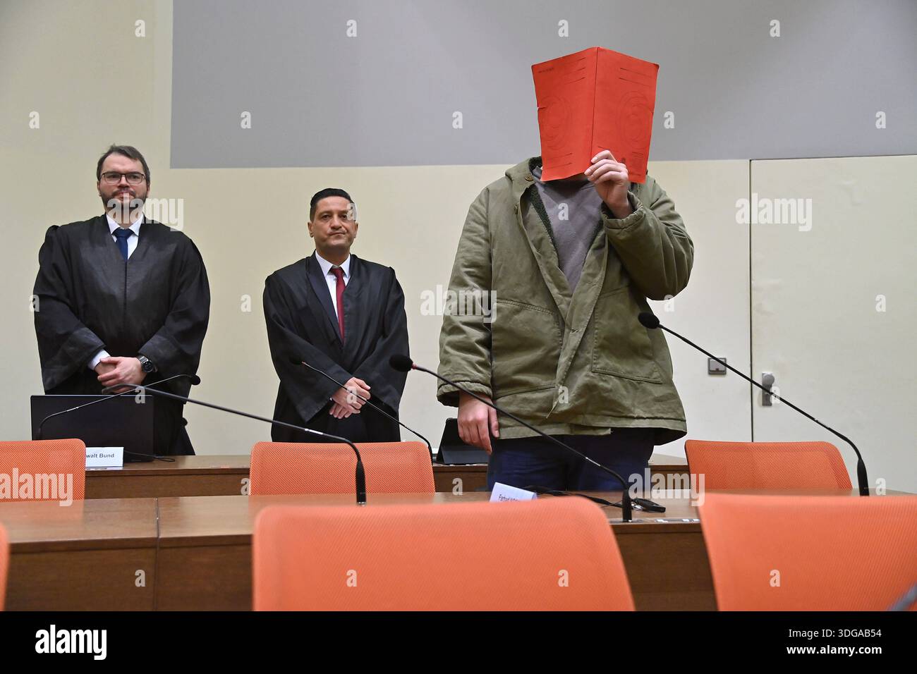Der Angeklage haelt einen Schnellhefter vor sein Gesicht. v.li:seine ...