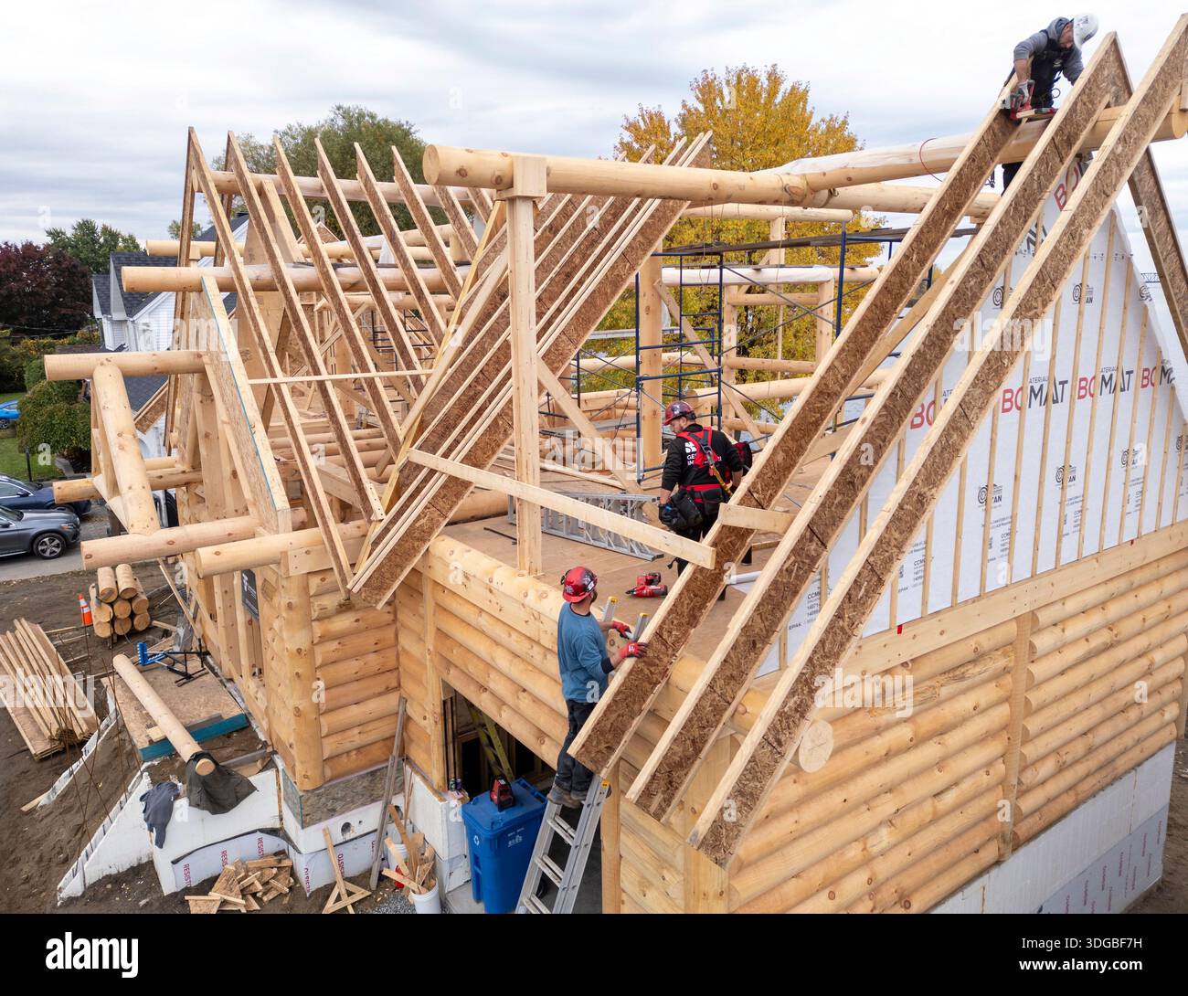 An aerial view shows carpenters building a log home made from white ...