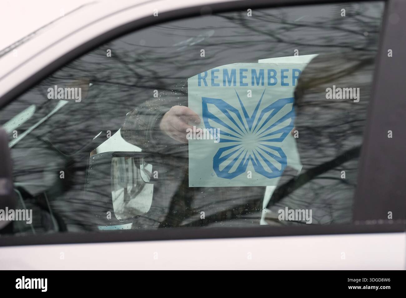 People hold up a sign as Federal Enforcement officers sit in a vehicle ...