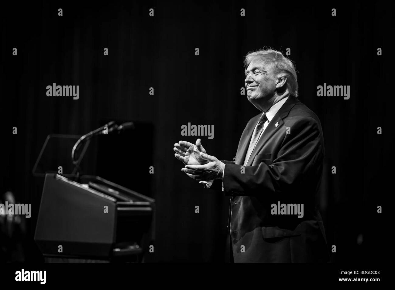 President Donald J. Trump applauds while standing beside a podium ...