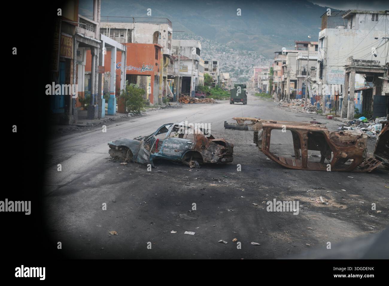 Burned cars block a street, seen from inside an armored police vehicle ...