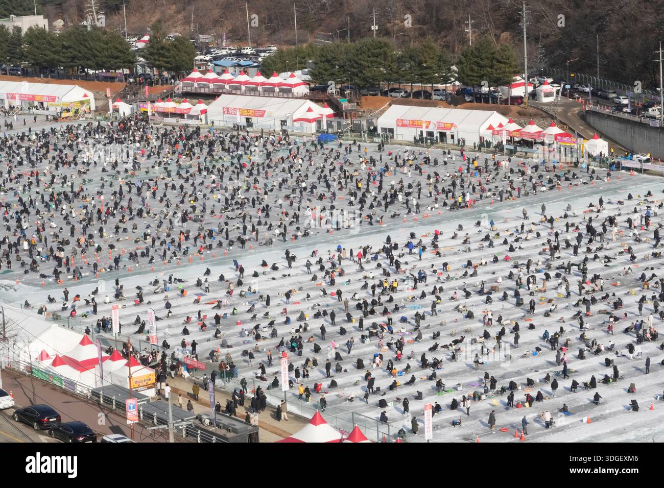 Participants fish through holes drilled in the surface of a frozen ...