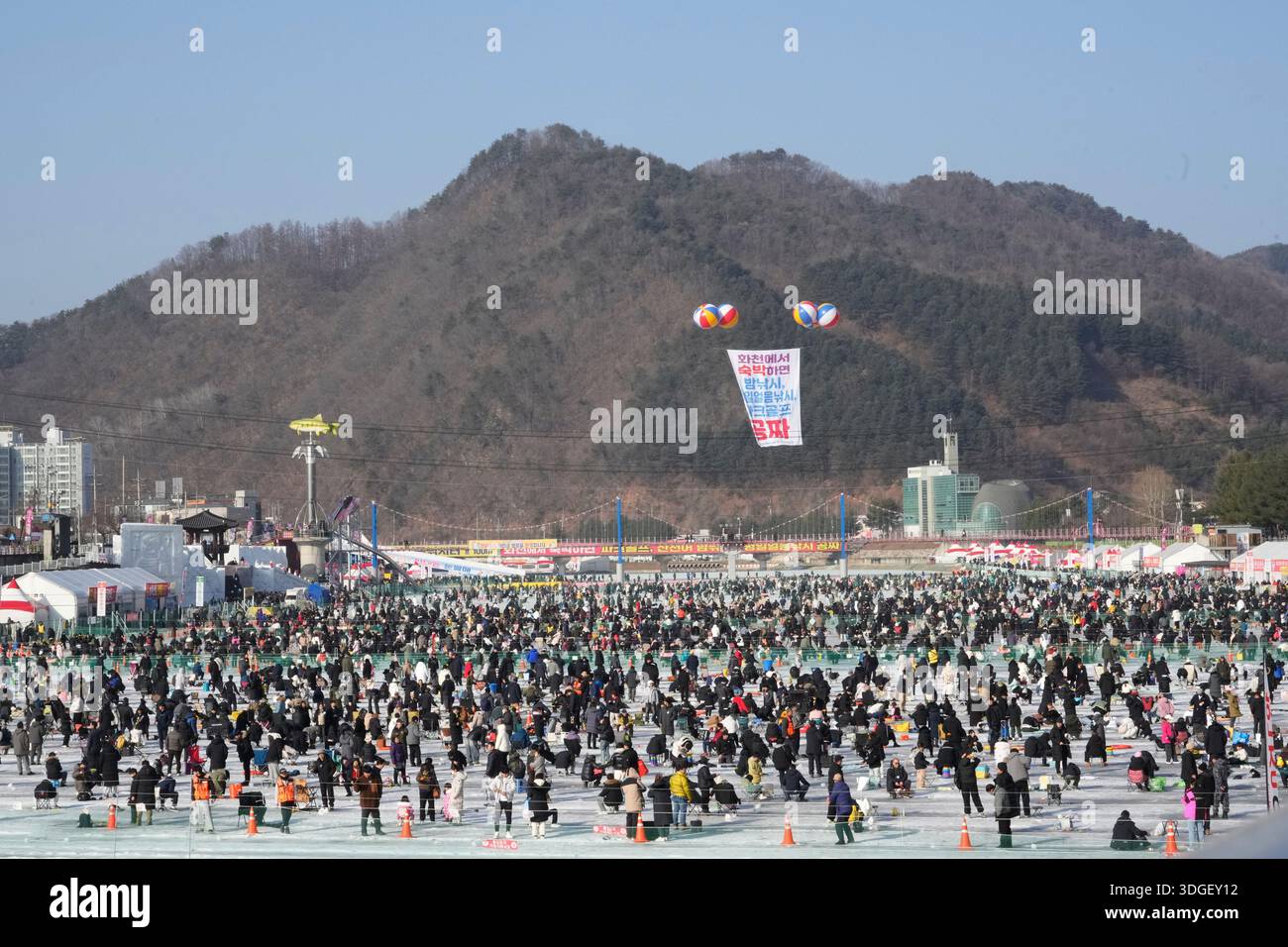 Participants fish through holes drilled in the surface of a frozen ...