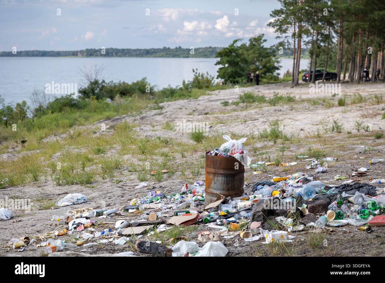 A distressing scene of pollution. A rusty barrel overflows amidst a ...