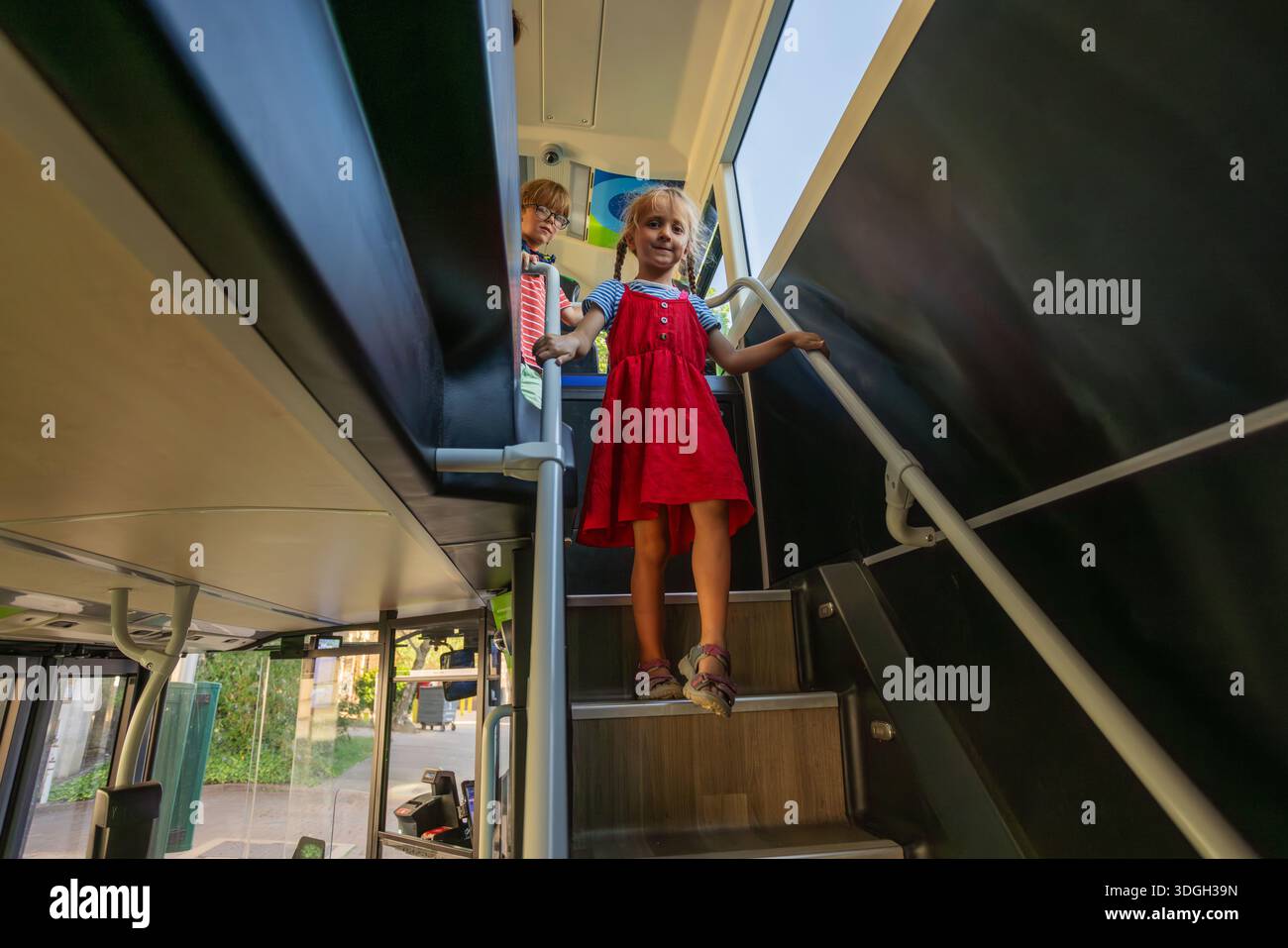 Two kids boy and girl are excitedly boarding a double decker bus, one ...