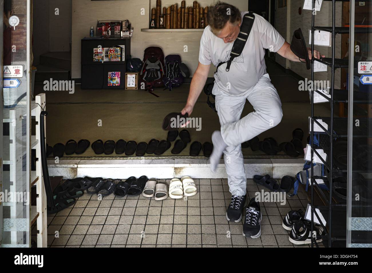 Man changes shoes at the entrance of a Japanese hotel. Traditional ...