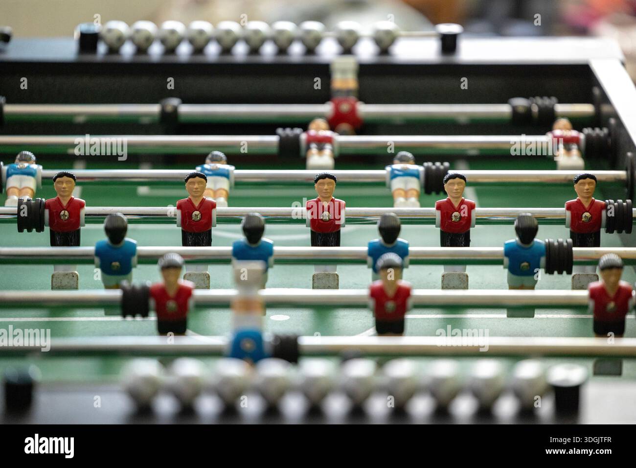 A foosball table with red and blue player figures mounted on metal rods ...
