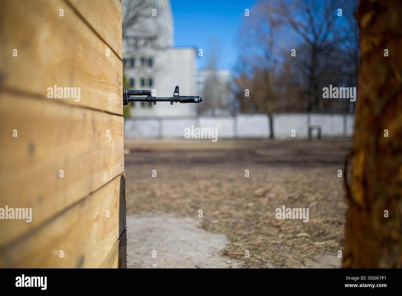 Black metal barrel of a Kalashnikov assault rifle aims from behind a ...