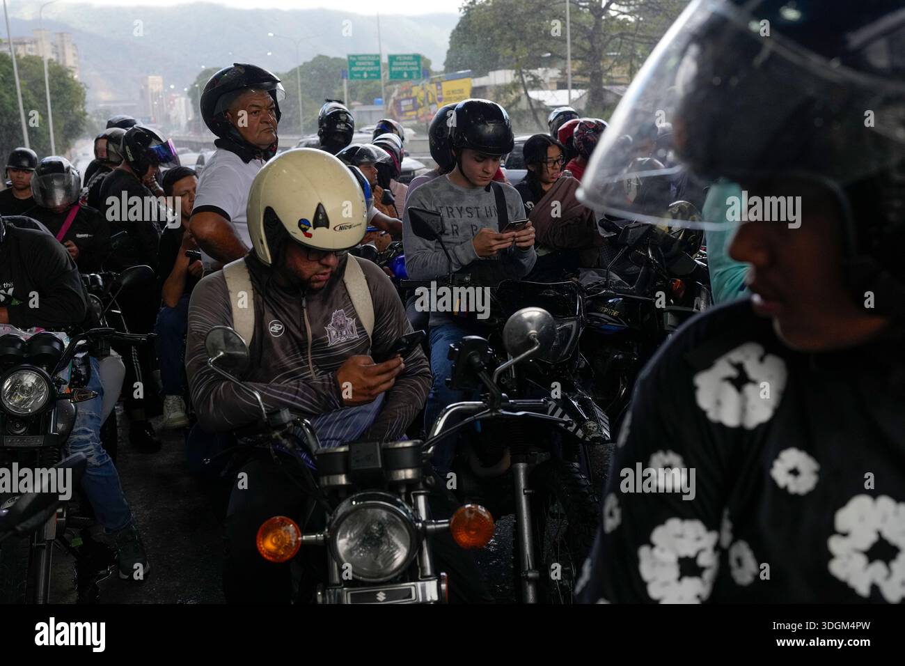 Motorcyclists wait for the rain to stop under a bridge in Caracas ...