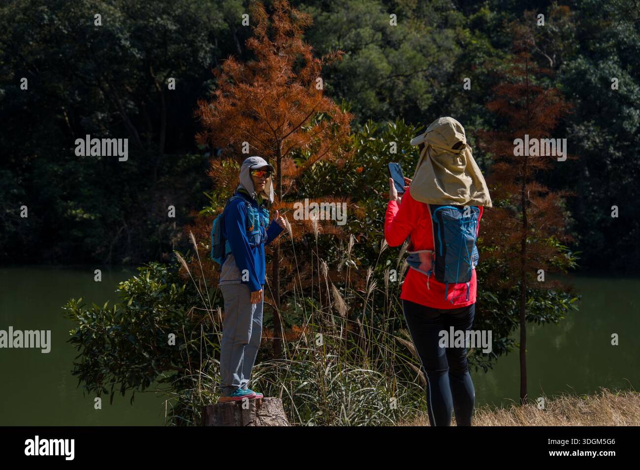 A man posing for a photo with trees with yellow, orange, and reddish ...