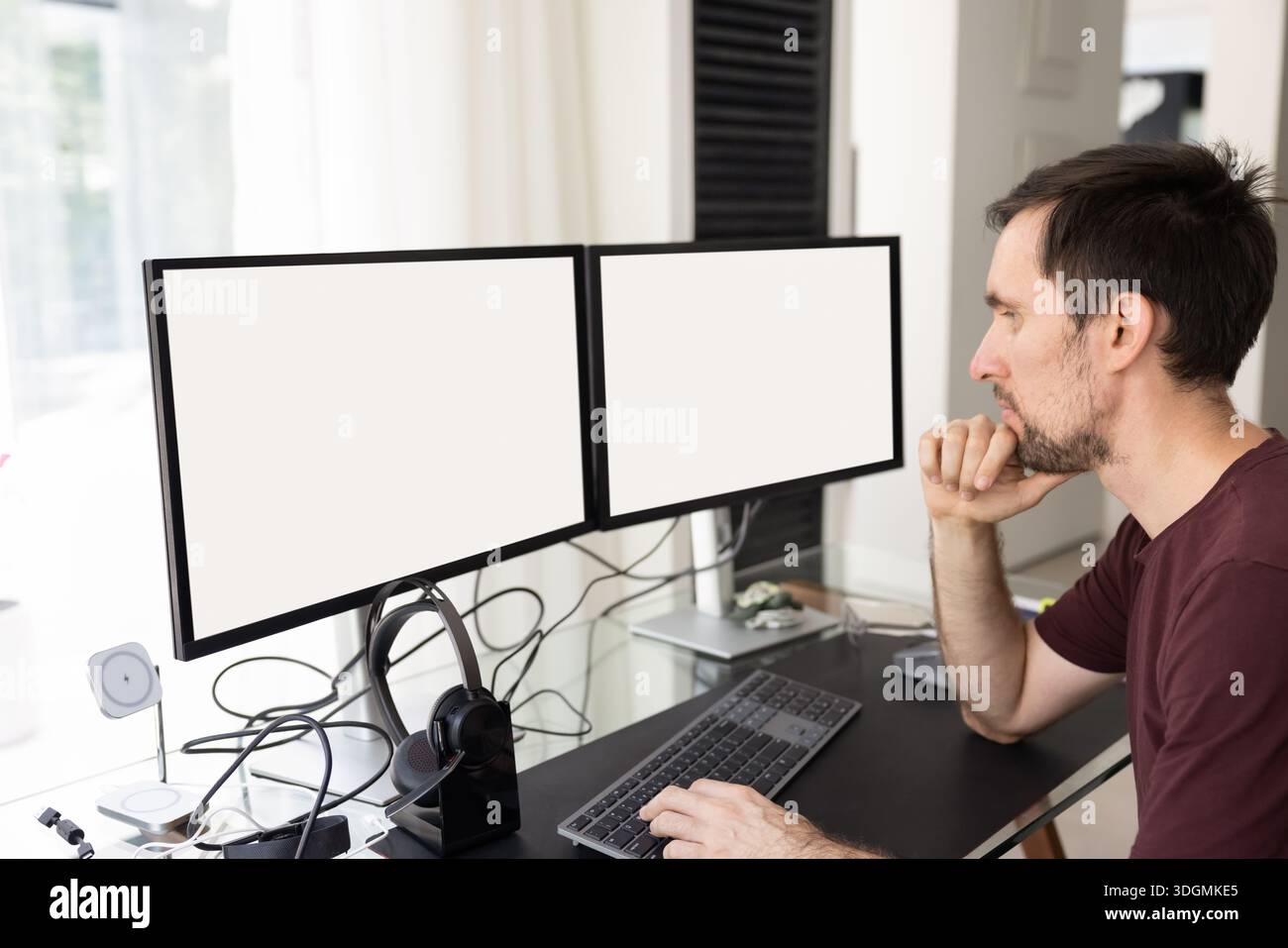Focused busy freelance professional man typing at two large monitors ...