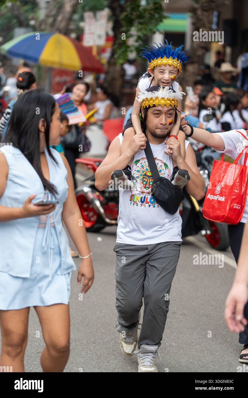 Smiling child with a colourful headdress held aloft on his fathers ...