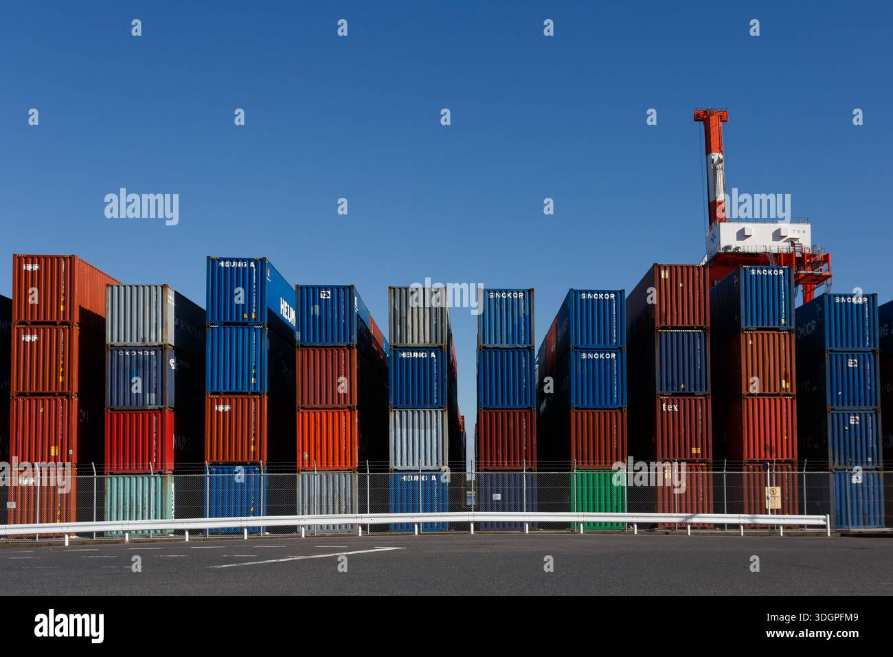 A container crane seen above stacked shipping containers at a wharf on ...