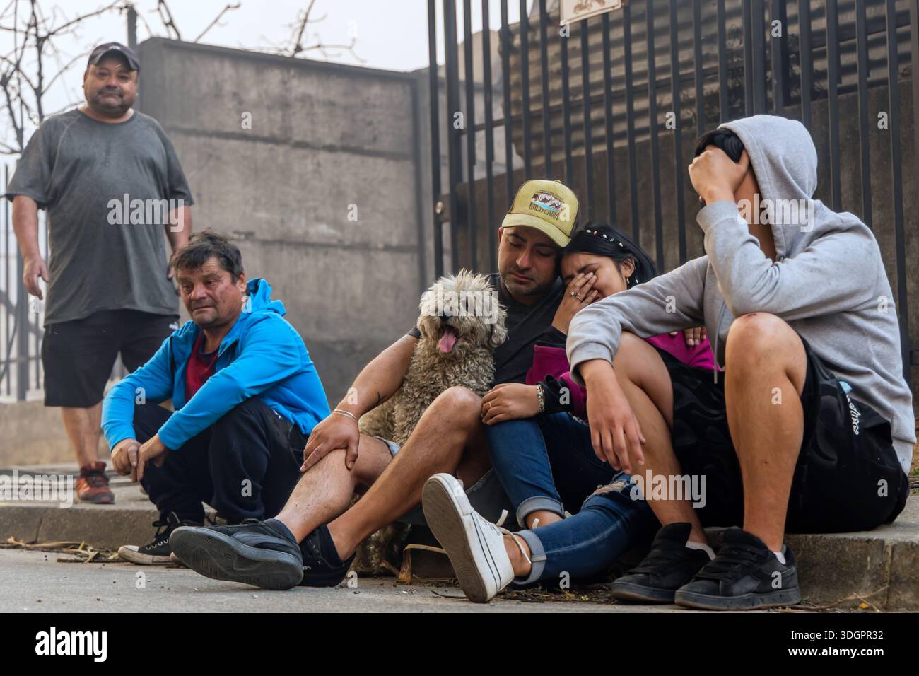 Members of the Gonzalez family sit on a sidewalk after their home ...