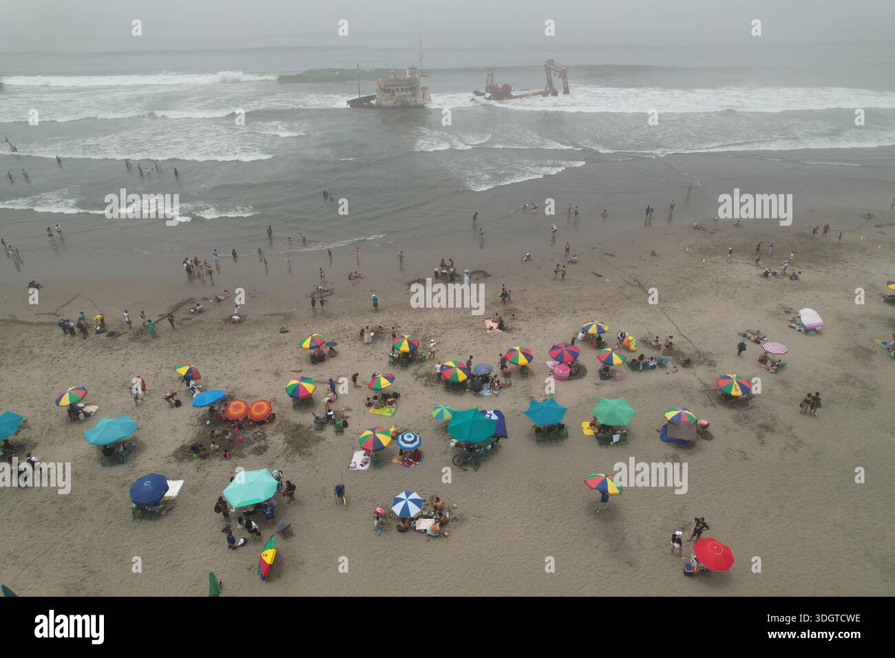 Beachgoers lounge in front of a stranded ship at Costa Azul beach in ...