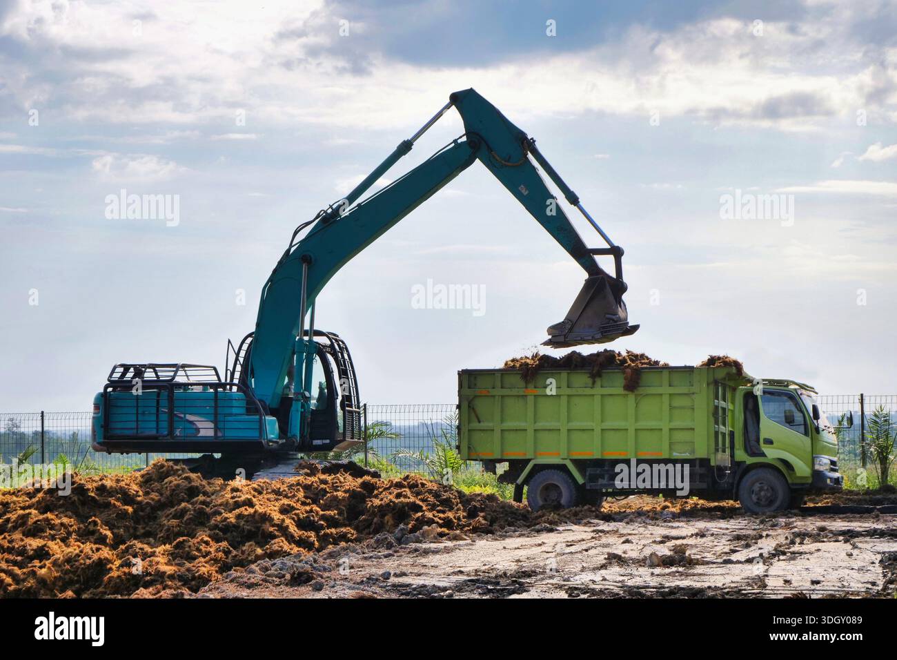 Eye-level industrial shot showing a heavy excavator loading organic ...