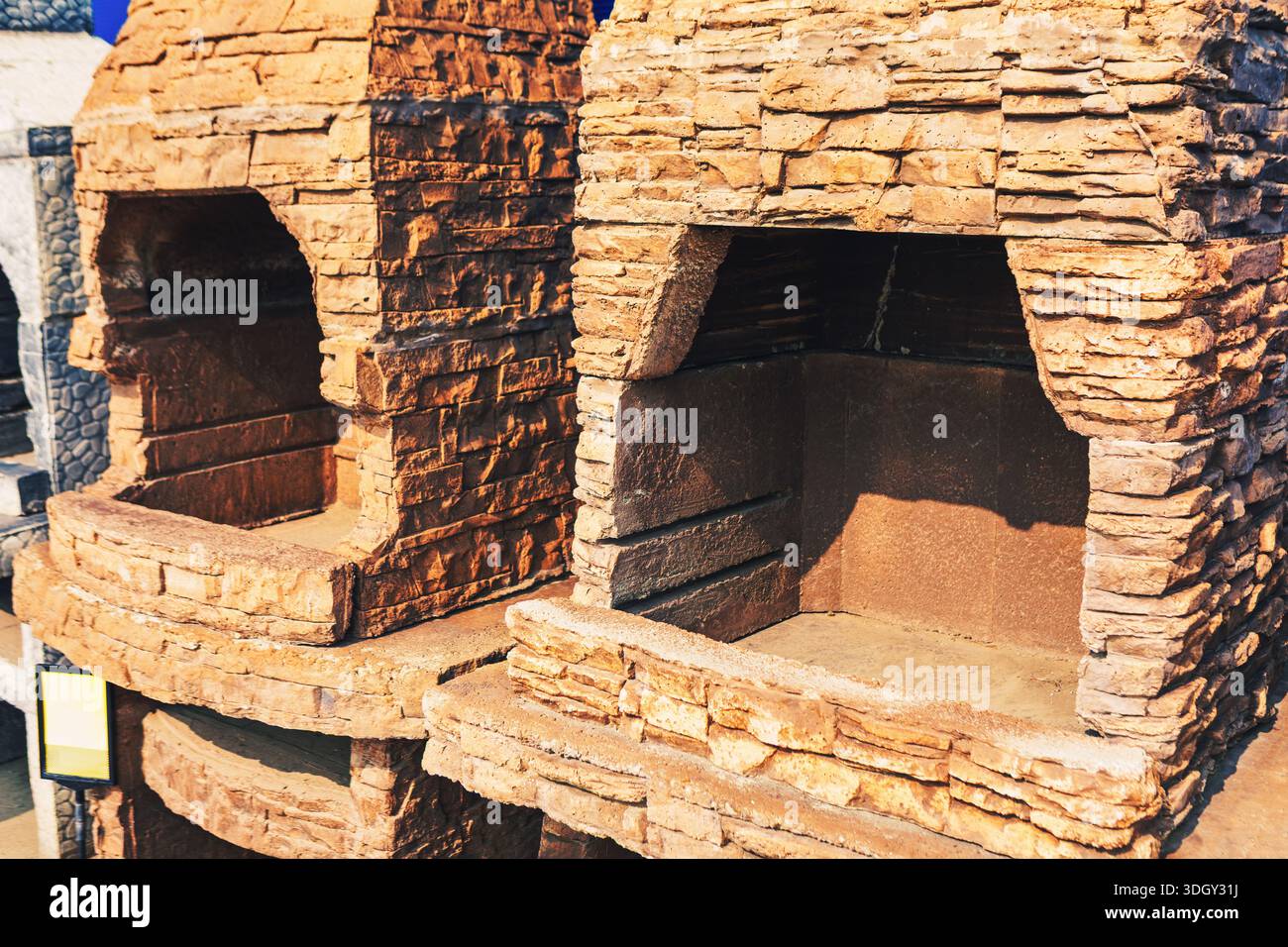 Outdoor ovens made from stacked stone veneer are displayed side by side ...