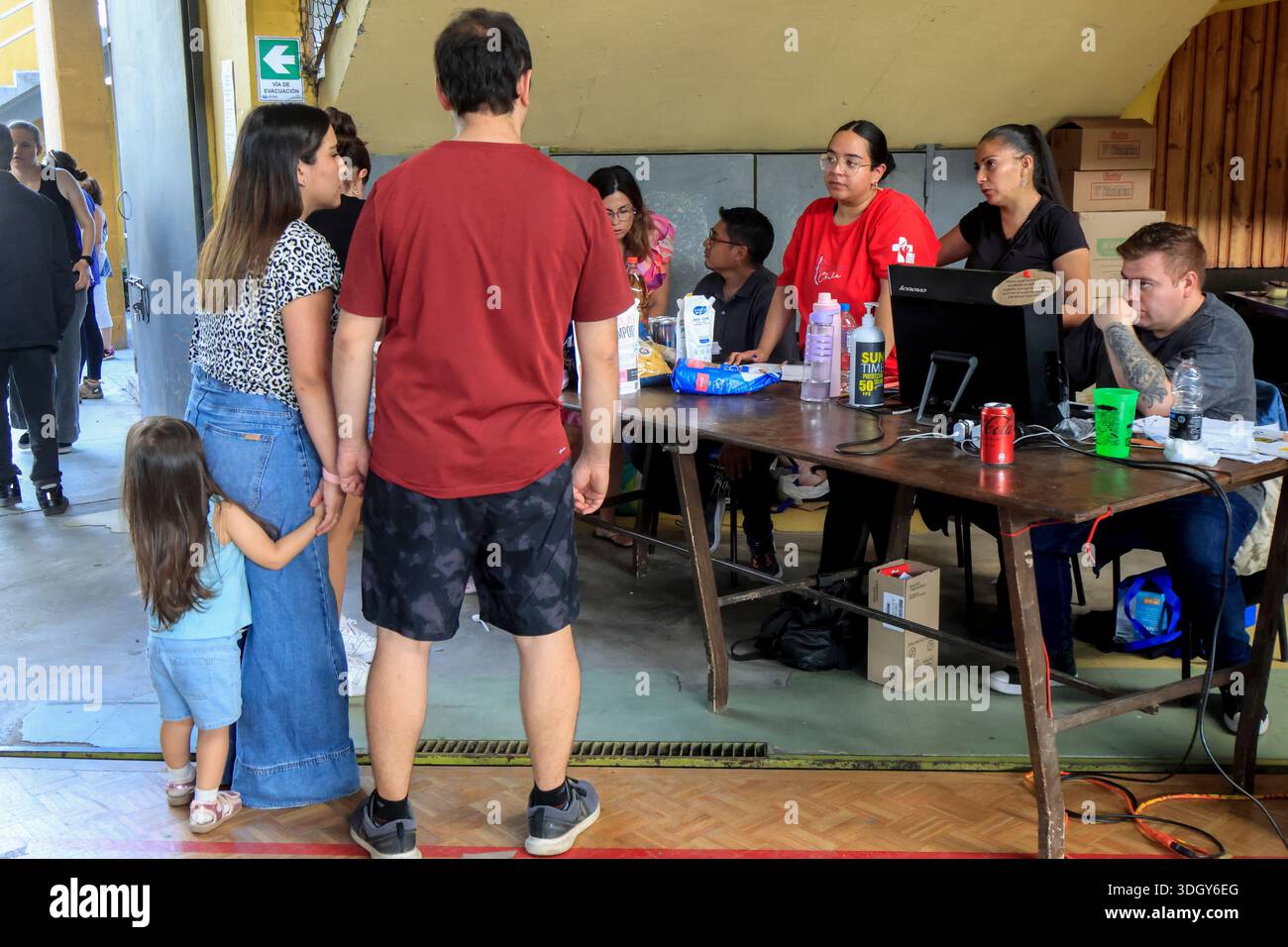 A little girl holds onto her mother while volunteers work at a ...
