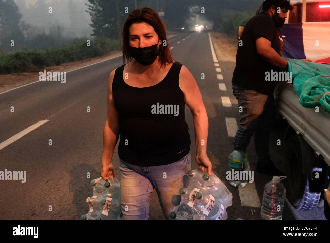 A woman carries bottles of water to help victims and workers at the ...