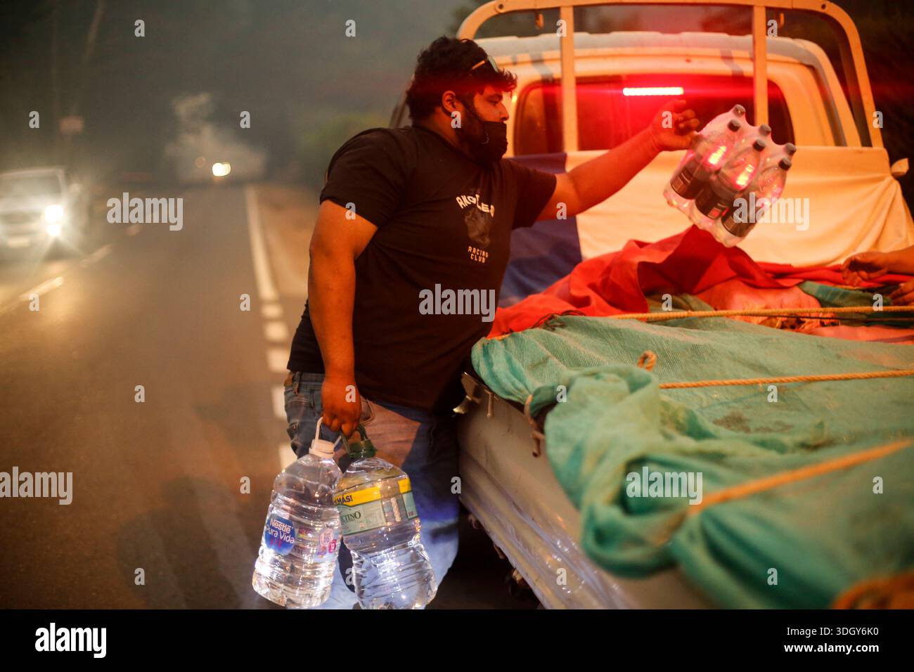 Concepcion, Chile. 18th Jan, 2026. A man carries bottles of water to ...