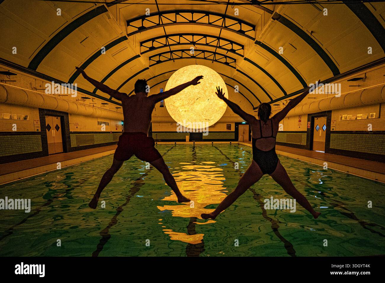 People jump into the water beneath Helios, an illuminated sun ...