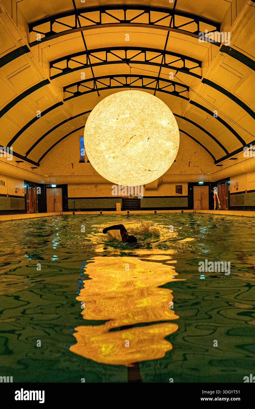 People swim beneath Helios, an illuminated sun installation by artist ...