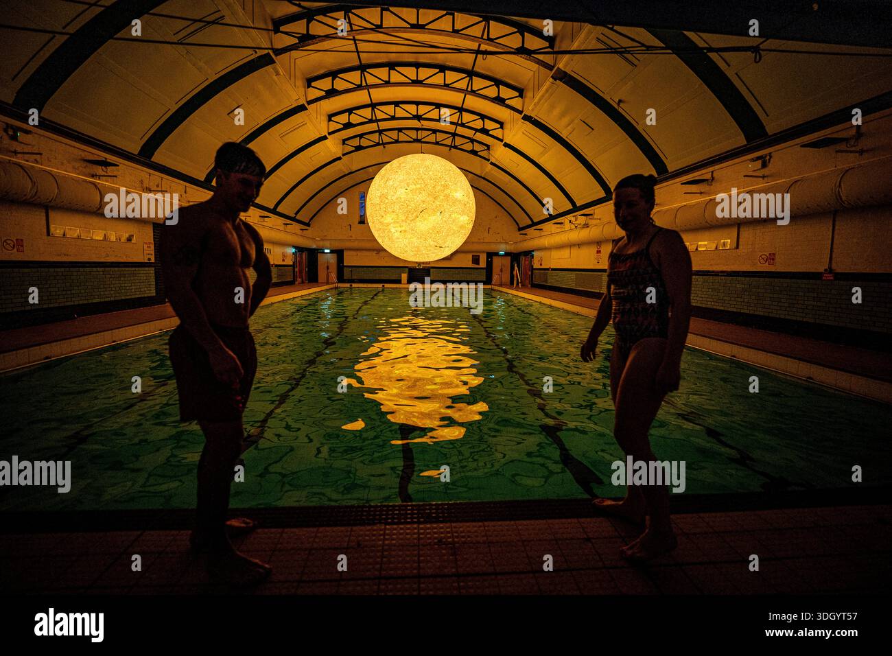 People get ready for a swim beneath Helios, an illuminated sun ...