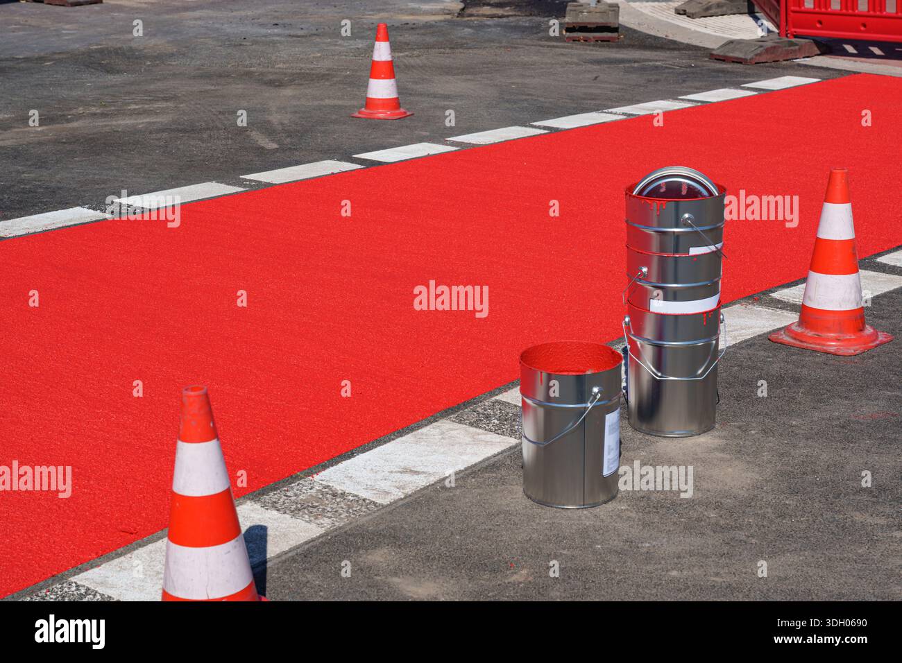 Fresh red bicycle lane marked with cones and cans during surface work ...