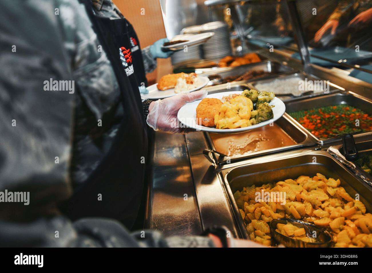 Military personnel serving food at a buffet line with various dishes ...