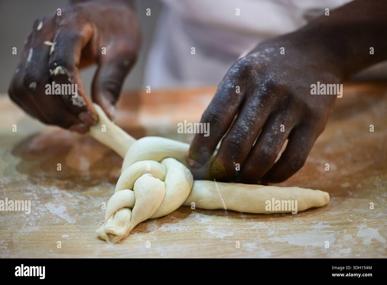 Berlin, Germany. 19th Jan, 2026. A baker braids a yeast plait at the ...