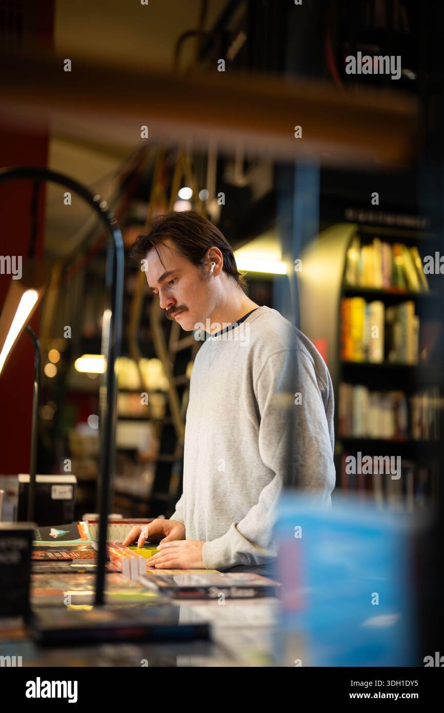 Thoughtful man booklover listening audiobook in pods and choosing ...