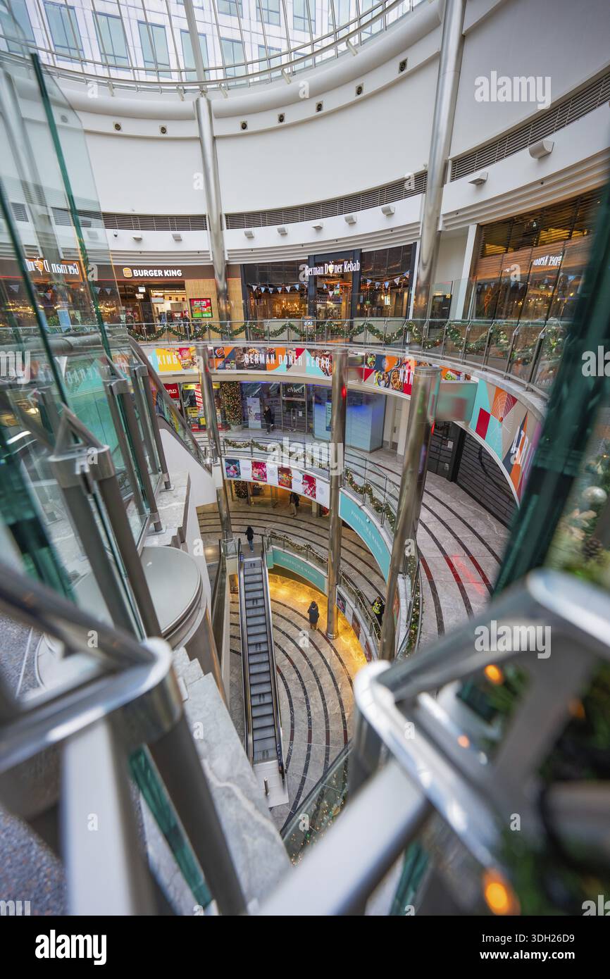 Multi-storey shopping center with escalators and shops behind glass ...