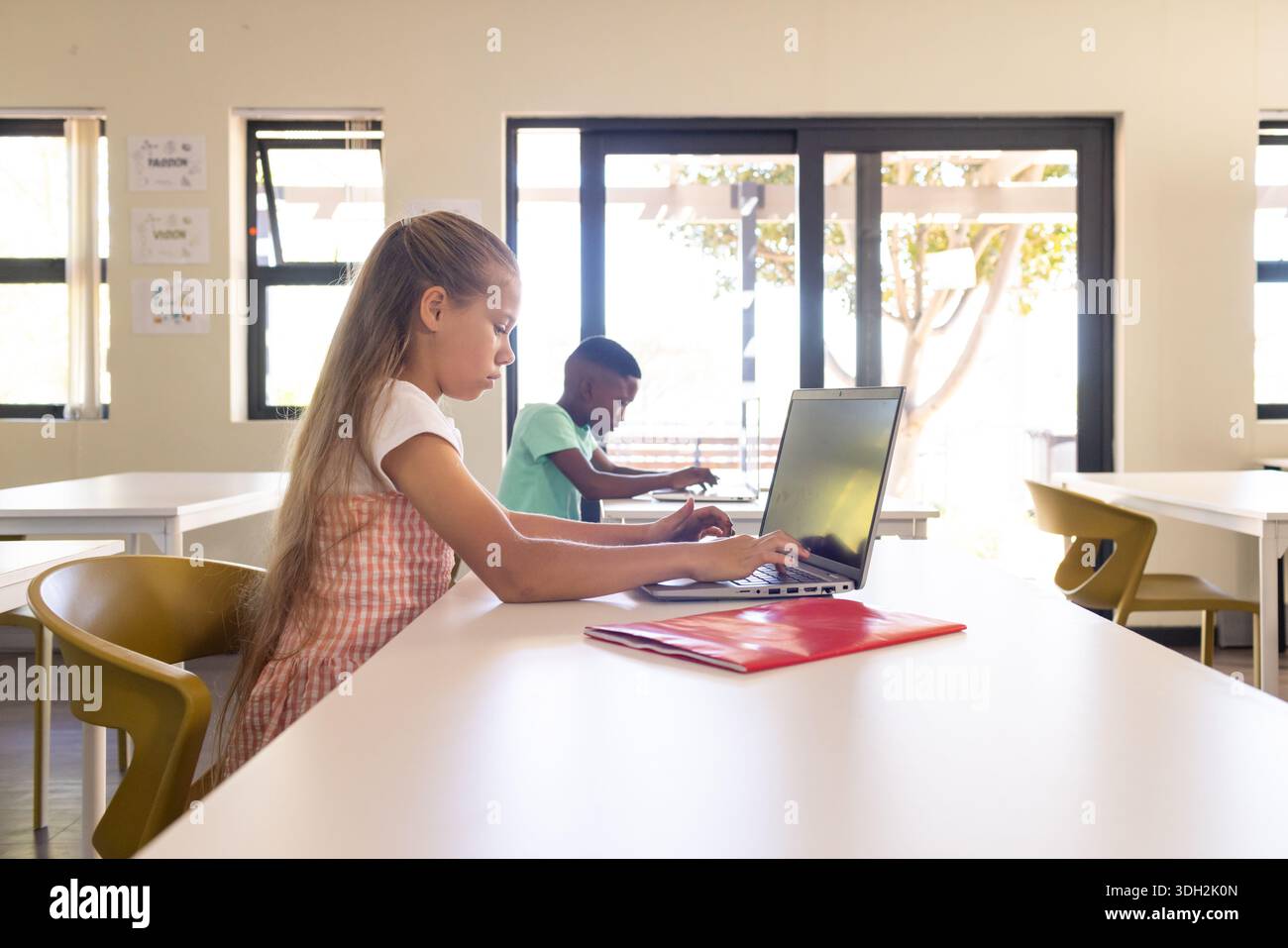 African American school-age classmates typing on laptops at school, red ...