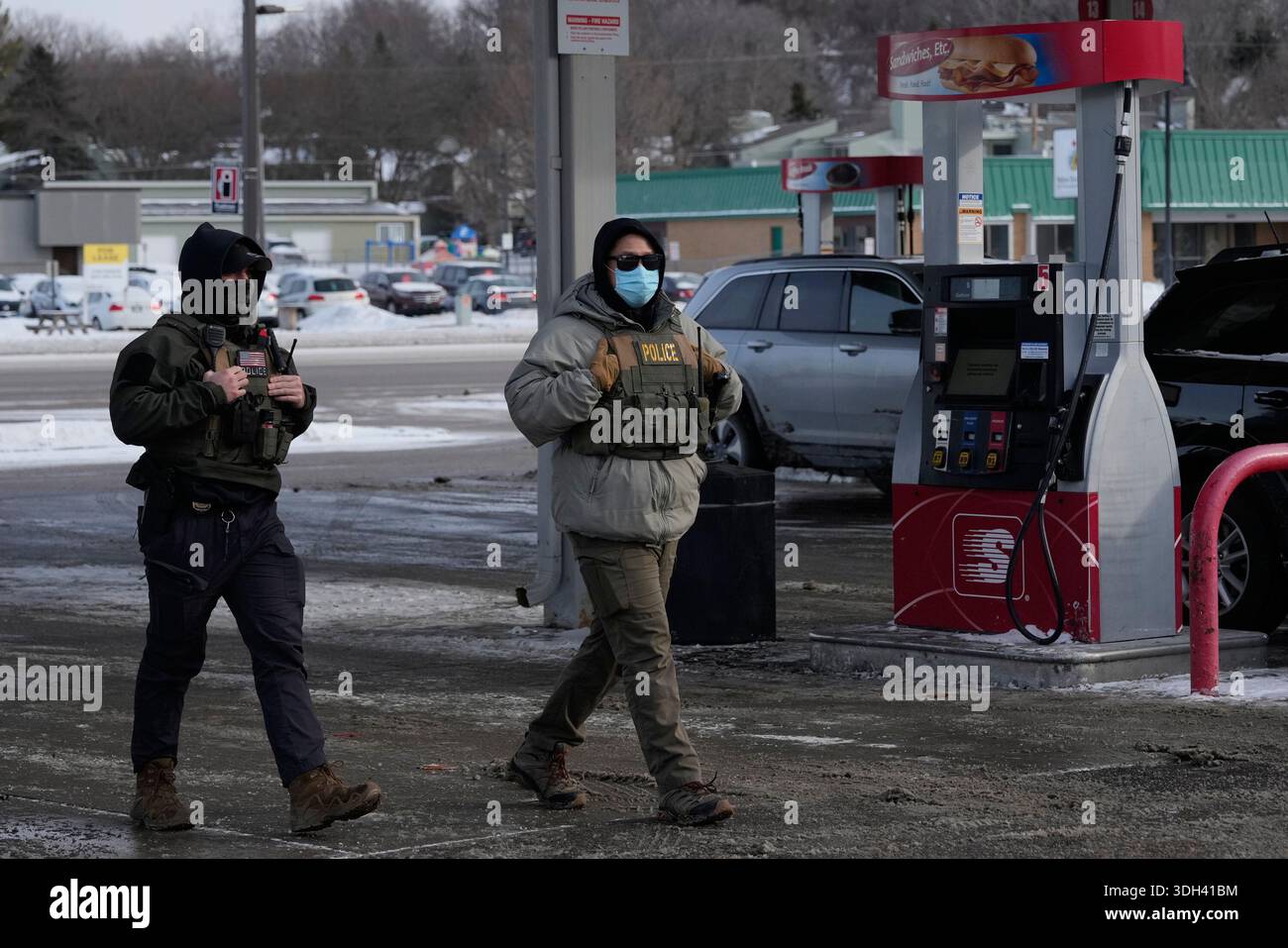 ICE agents walk through a gas station, Monday, Jan. 19, 2026, in St ...