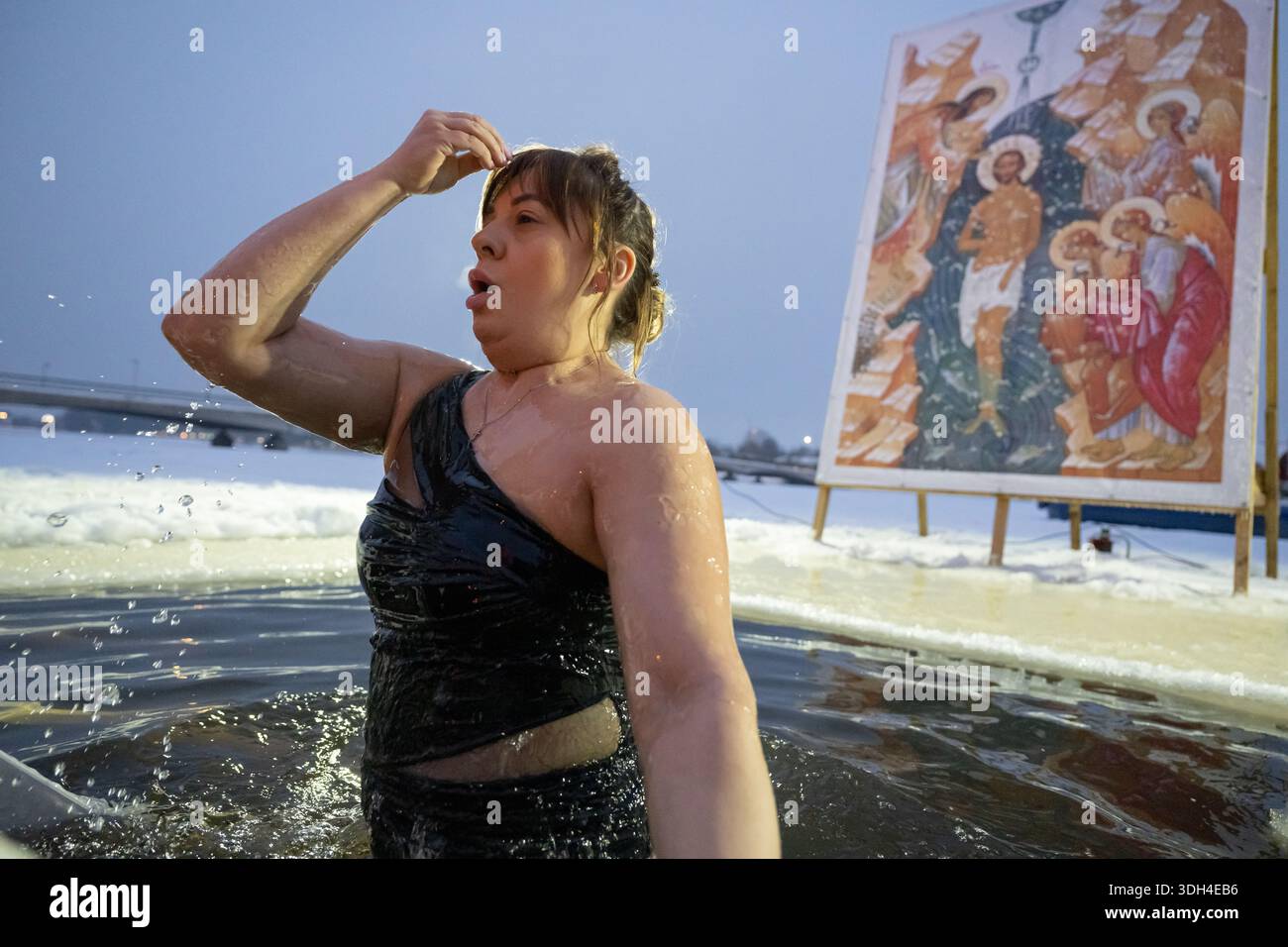 A woman immerses herself in the icy water of an ice hole during the ...