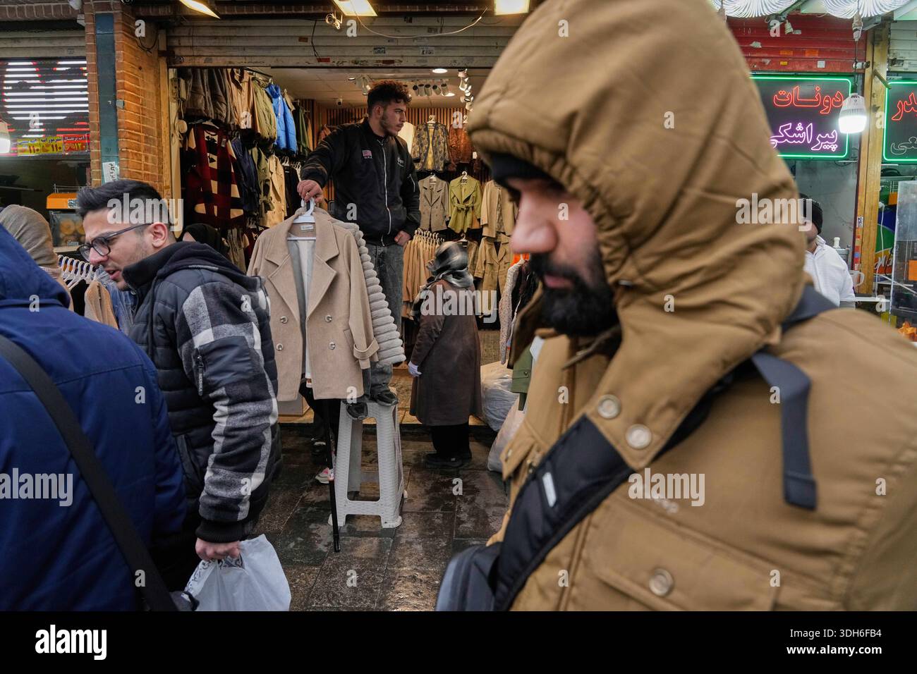 A shopkeeper holds garments at his store at Tehran's historic Grand ...
