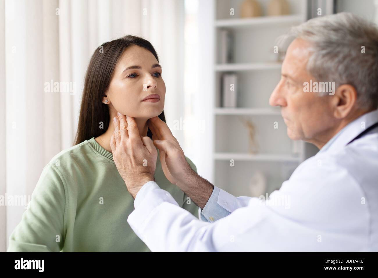 Male doctor palpating neck lymph nodes of female patient in clinic ...