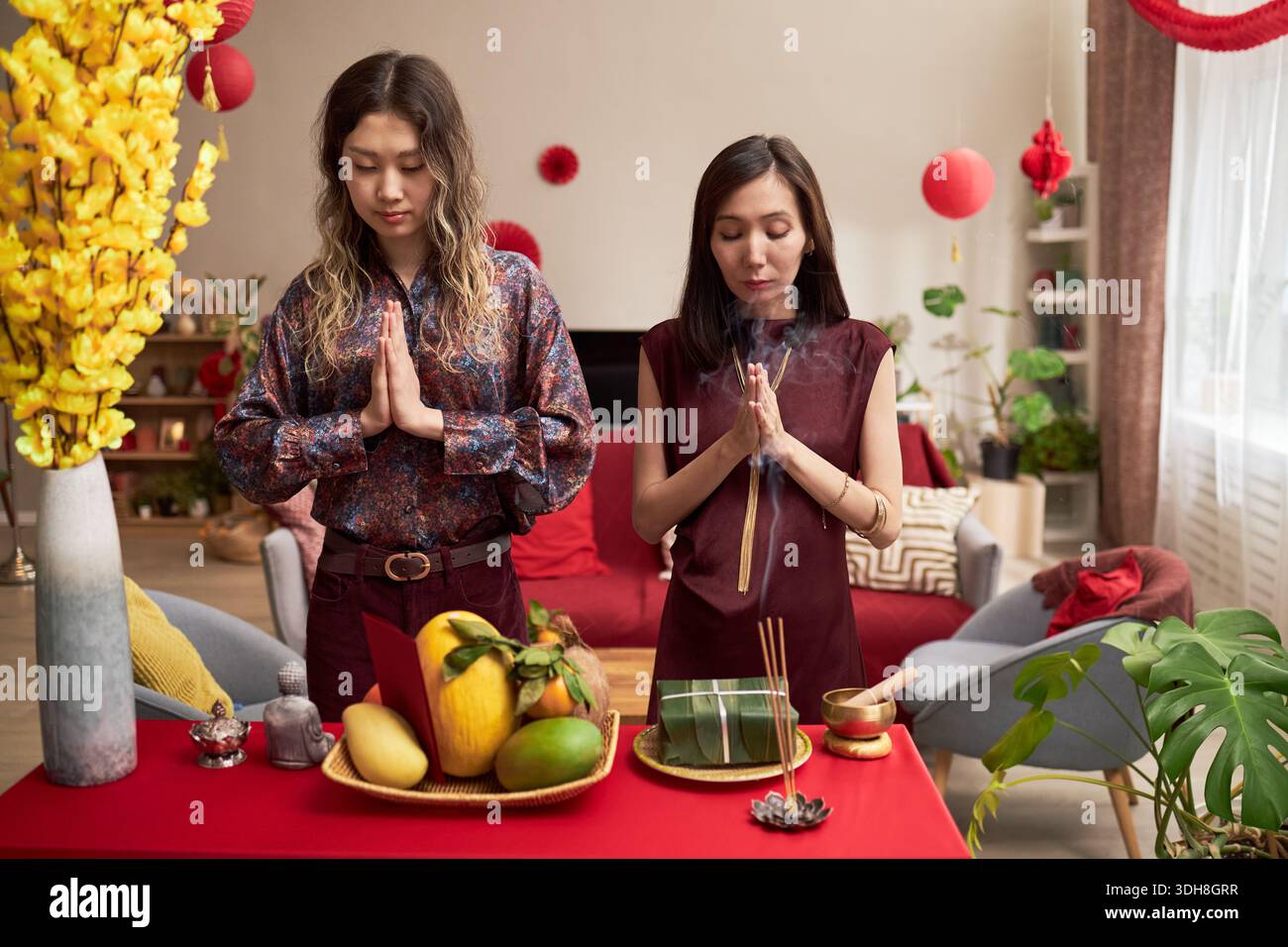 Two young adult Asian women standing with hands pressed together ...