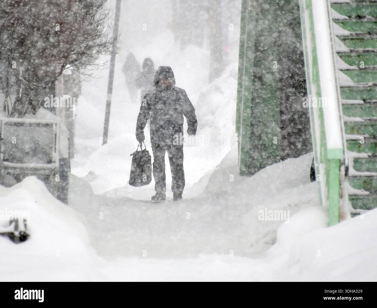 People walk on a snow-covered street in the snowfall in Sapporo City ...