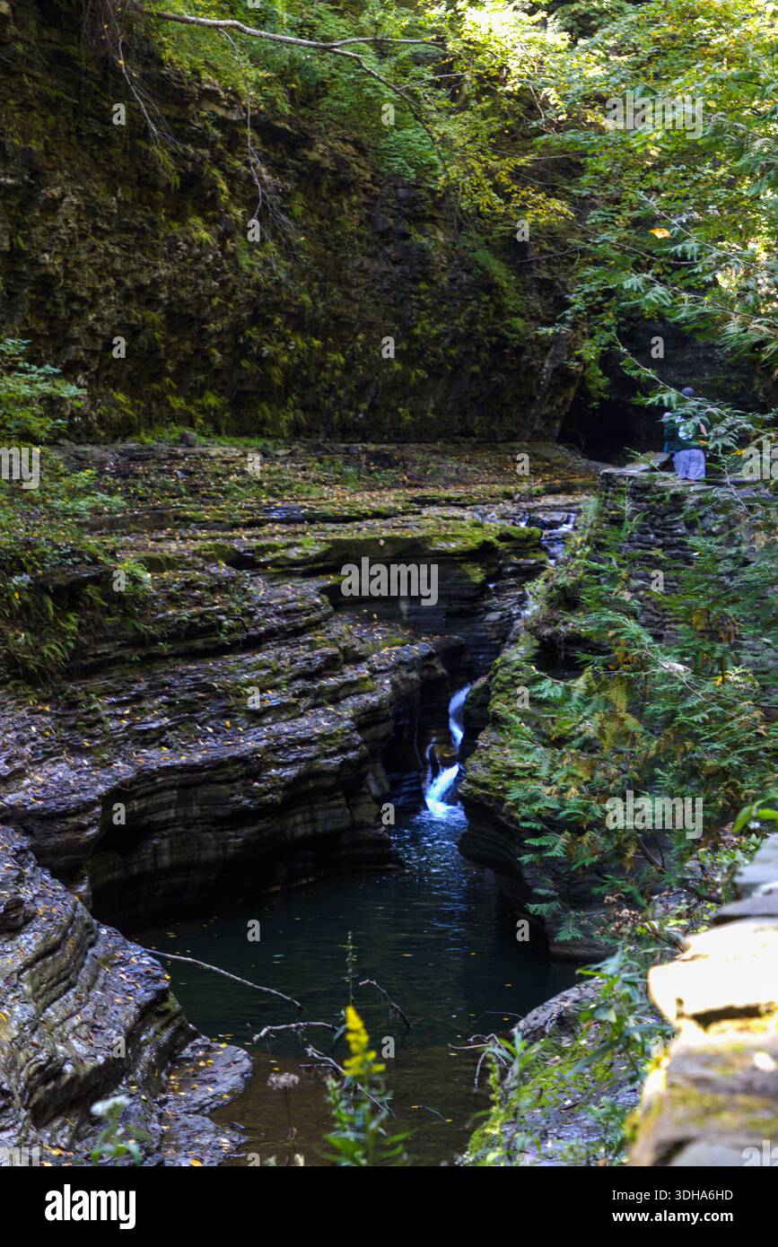 Narrow canyon pool with dark water surrounded by layered rock walls and ...