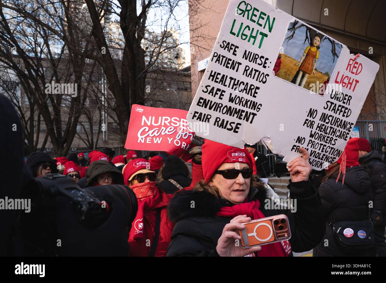 A nurse with a sign that lists benefits of a new contract versus the ...