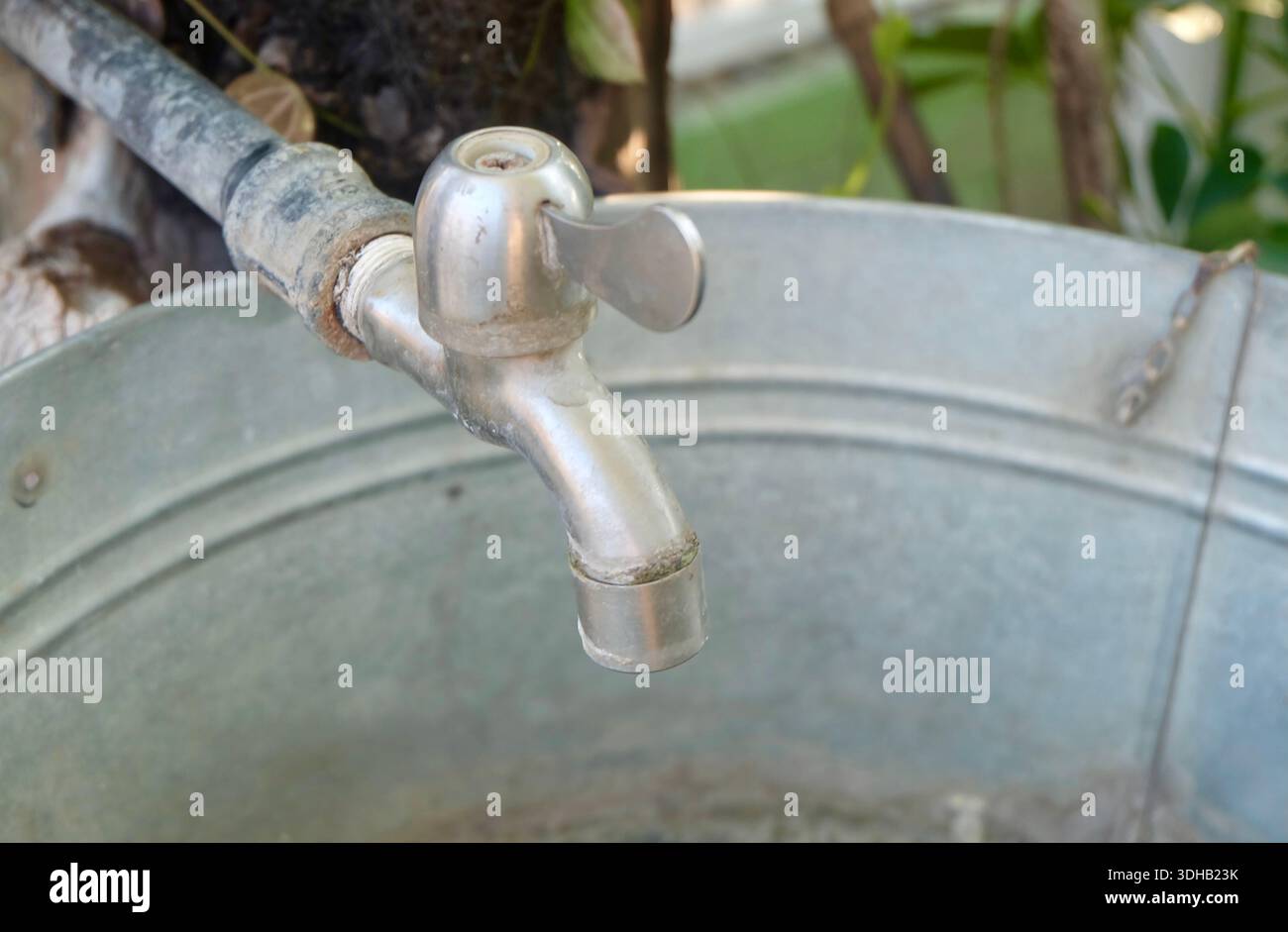 Outdoor silver faucet attached to metal basin delivering water flow in ...