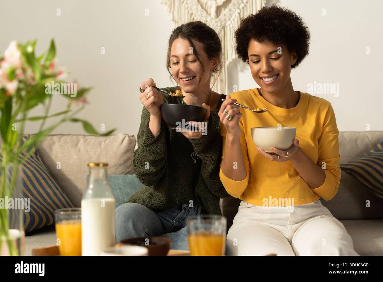 Two women enjoy breakfast together, smiling and laughing in a warm ...