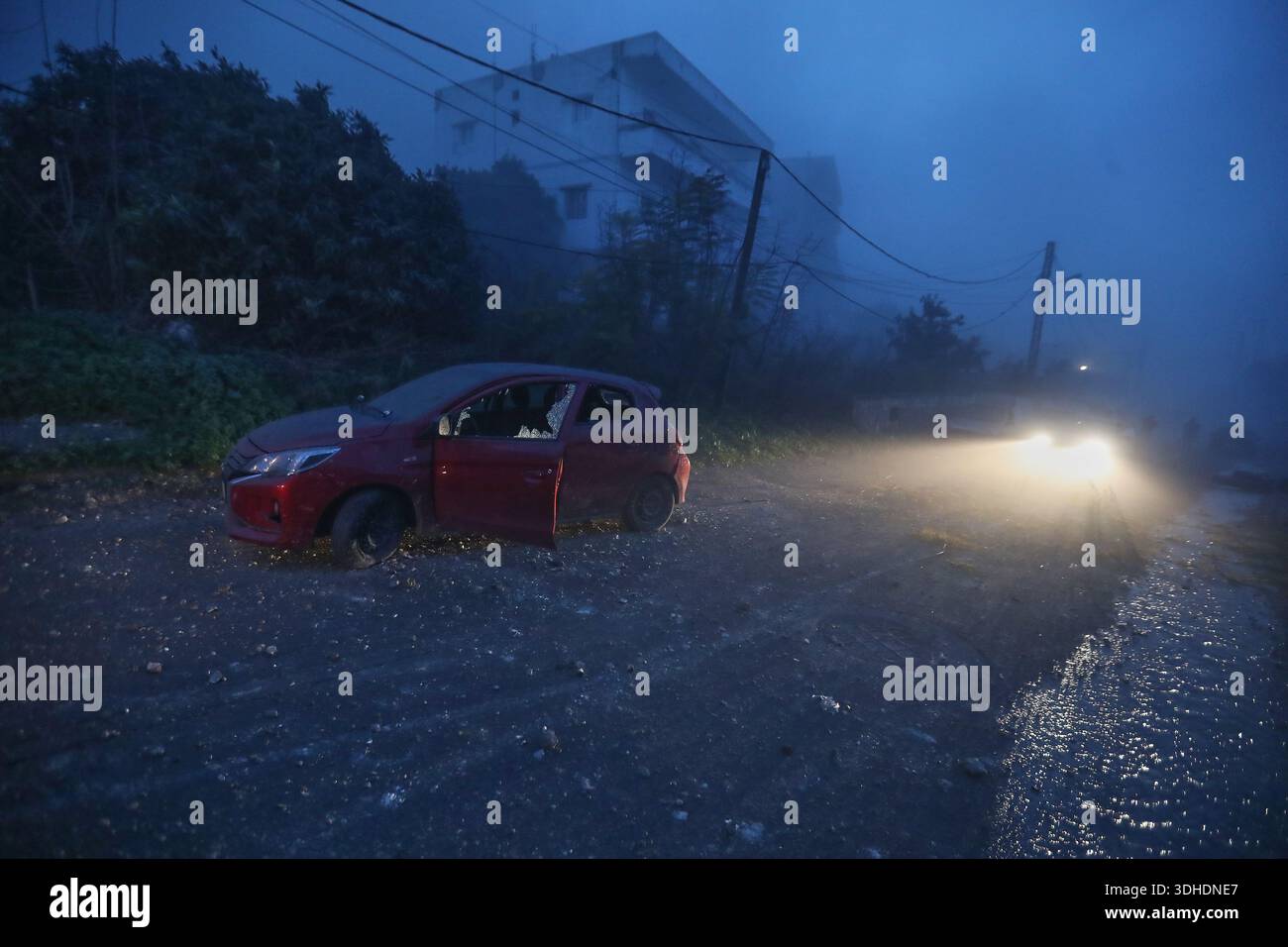 A damaged car is seen at the side of an Israeli airstrike in Qennarite ...