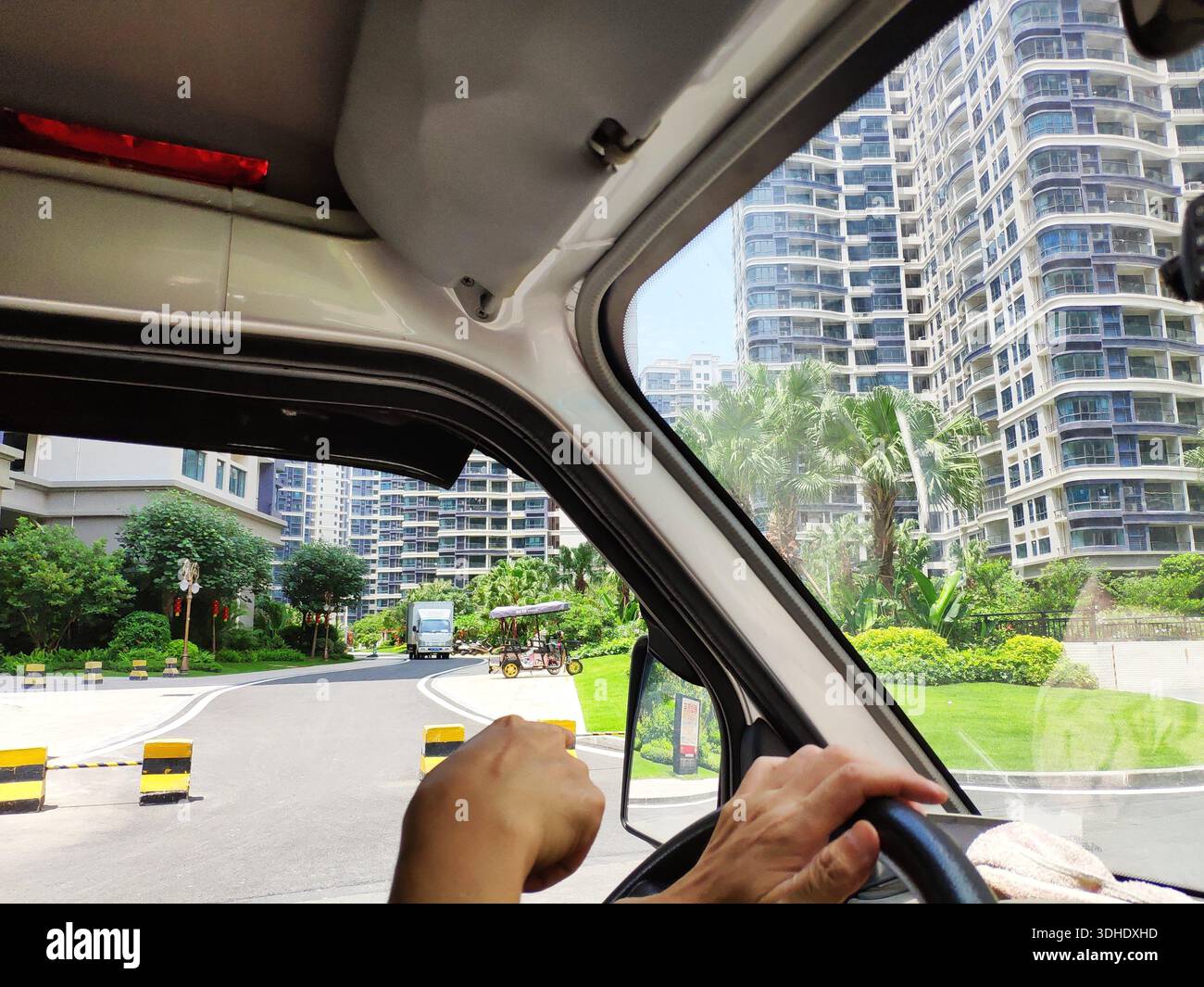 Hands on steering wheel from inside a vehicle driving through a modern ...